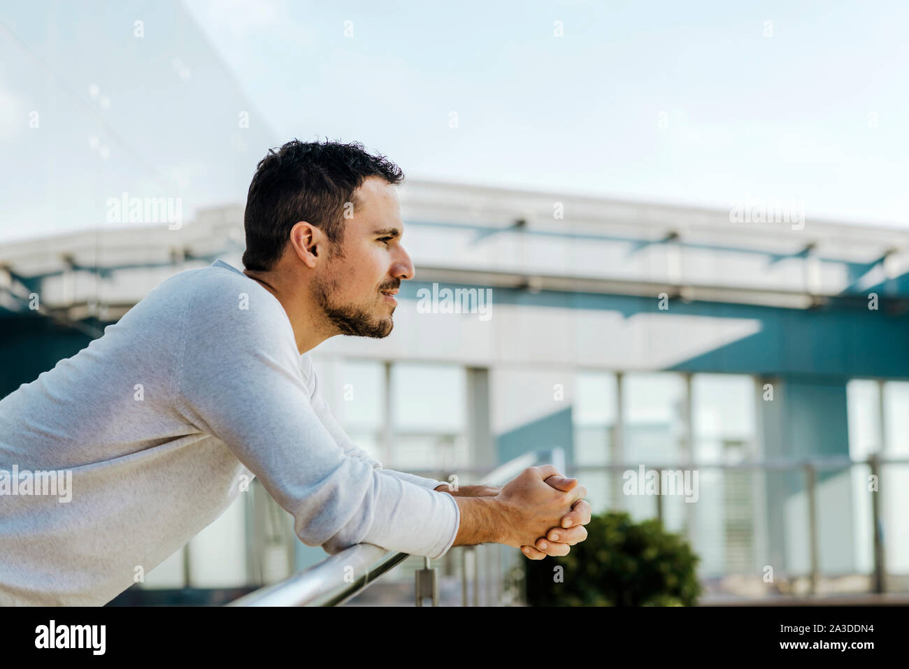 Man leaning on railing of footbridge looking at distance Stock Photo ...