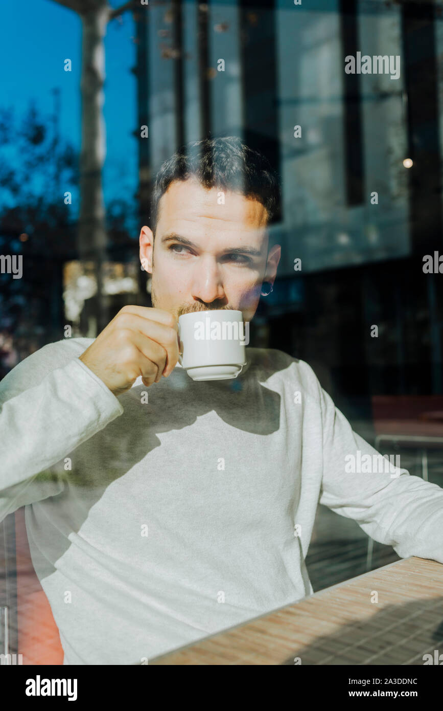 Man drinking coffee while looking away in a cafe shop Stock Photo - Alamy