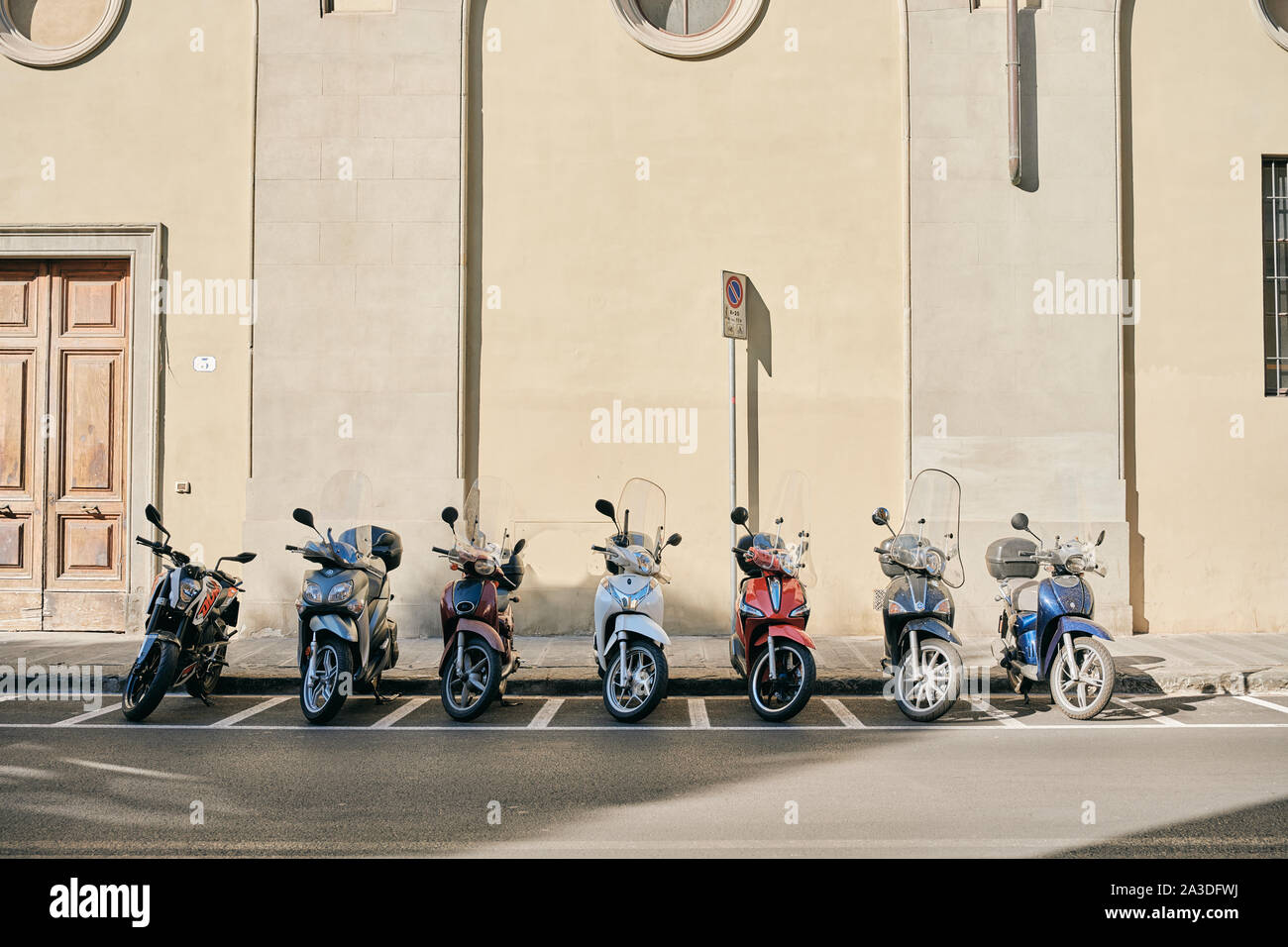 Modern shiny scooters parked along old classic building at Italian city ...