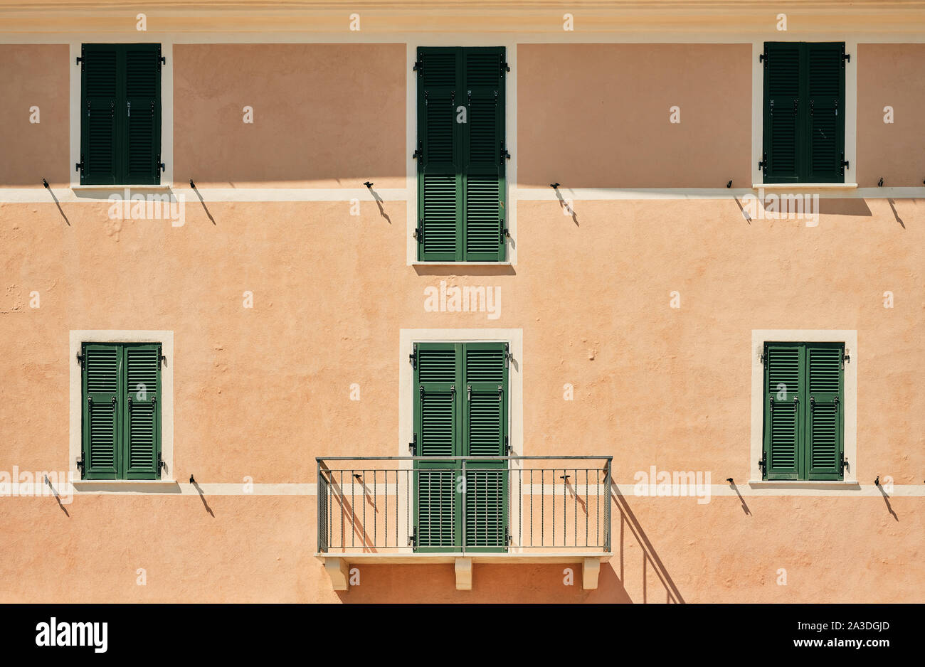 Beige building wall with green windows and doors facing out in strict ...