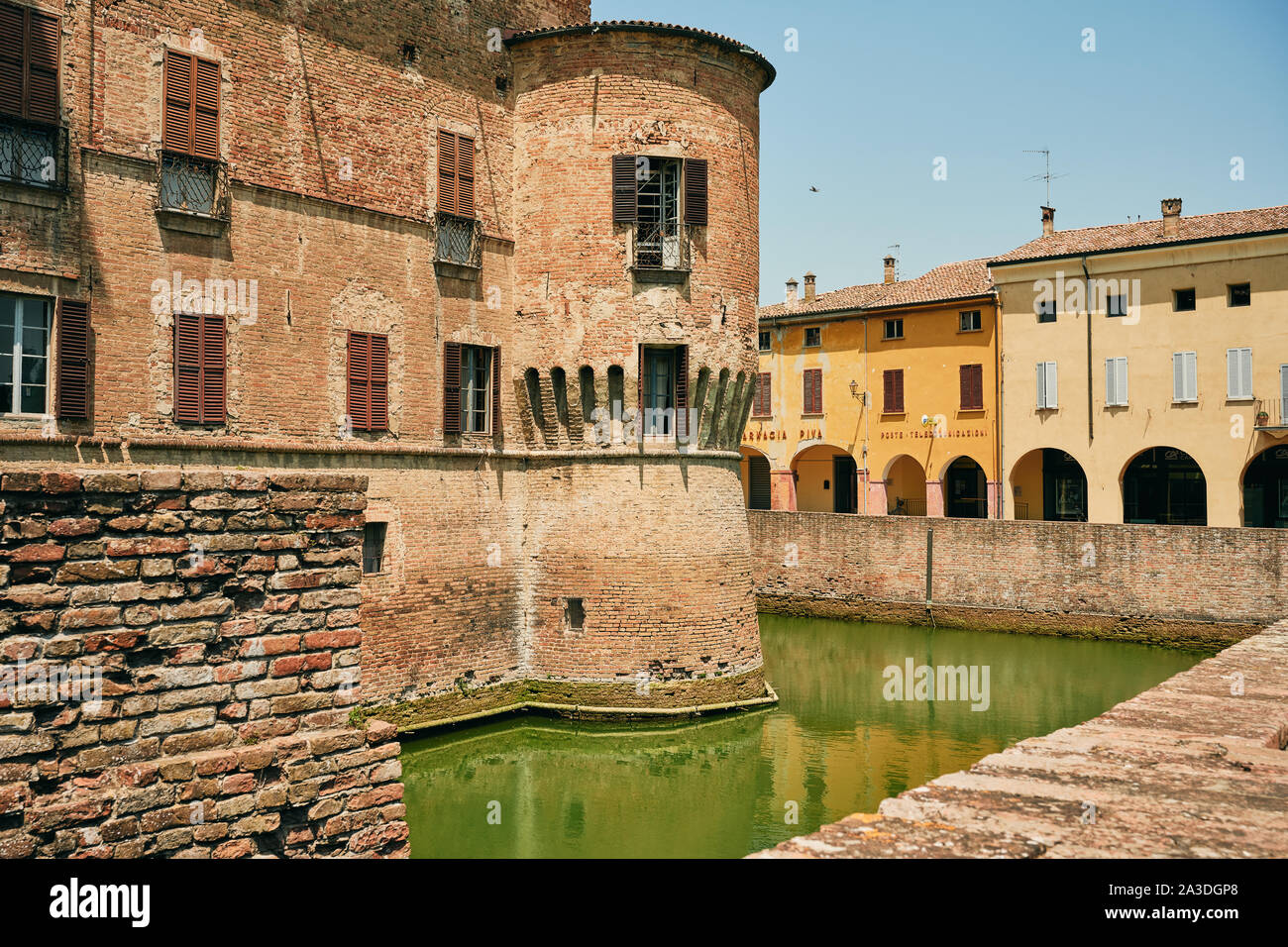 Round brick tower on corner of old building and green water in canal ...