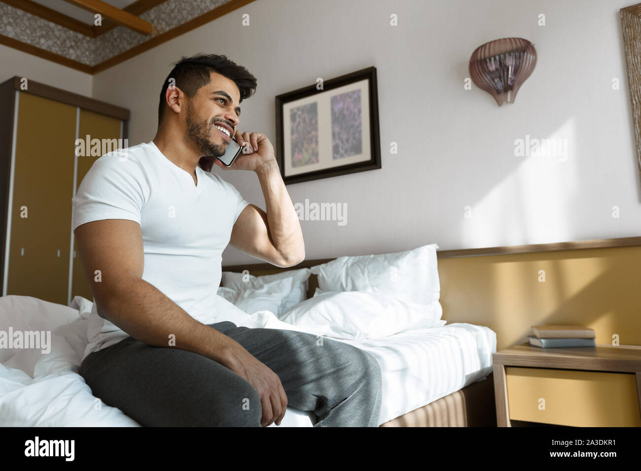 Cheerful guy talking on phone in bed Stock Photo - Alamy