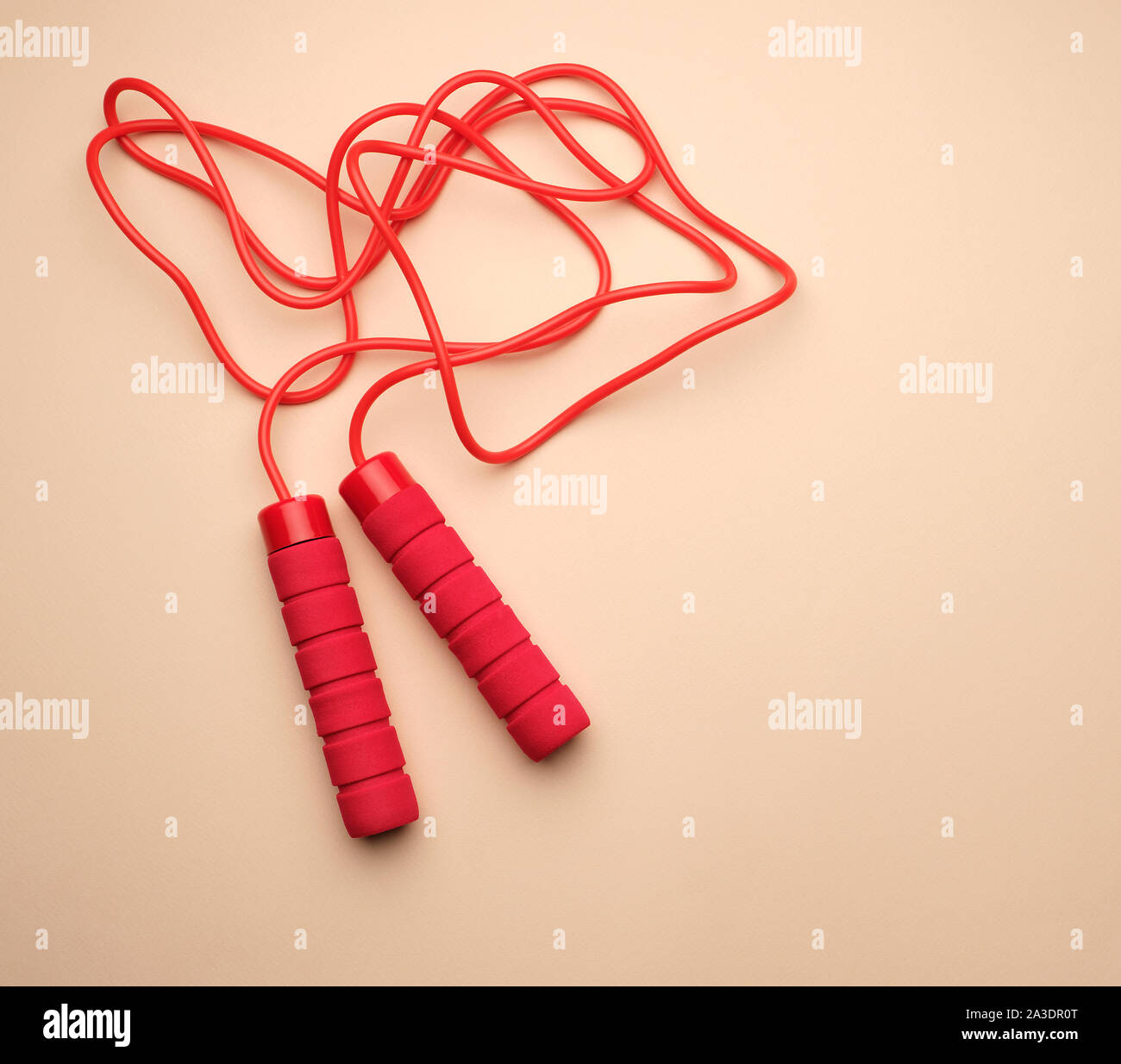 red sports rope for jumping and cardio load on a beige background ...