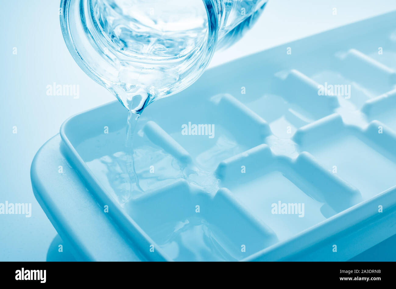 closeup pouring fresh drink water from a jug into ice cube tray Stock Photo - Alamy