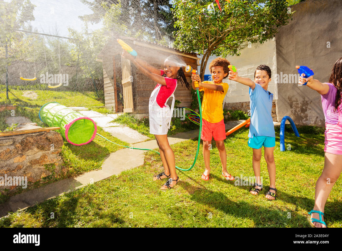 Group of kids play fun wet game with water pistols Stock Photo - Alamy