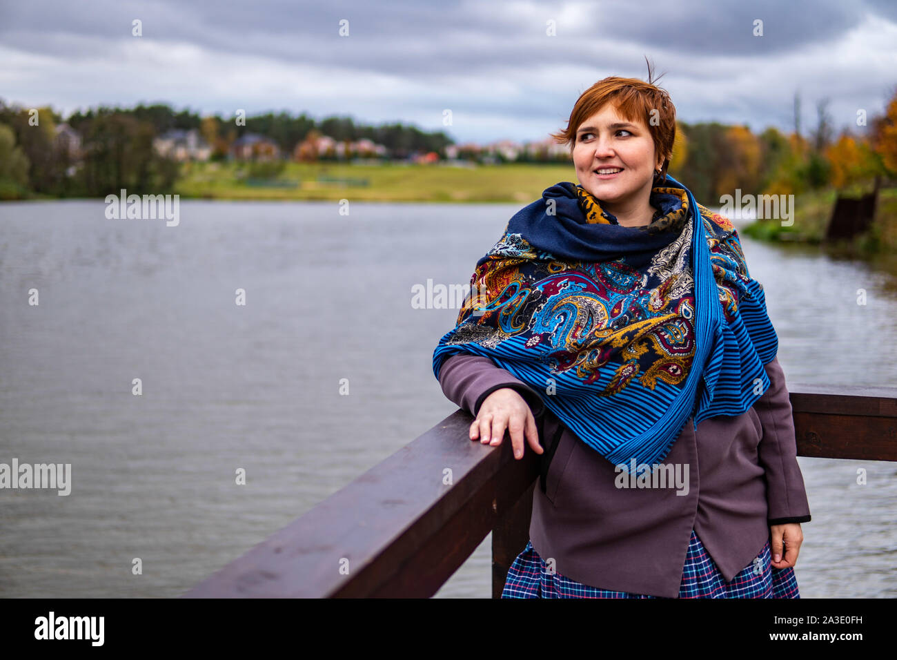 Fat girl thought on the lake, cloudy weather, in a beautiful scarf red ...