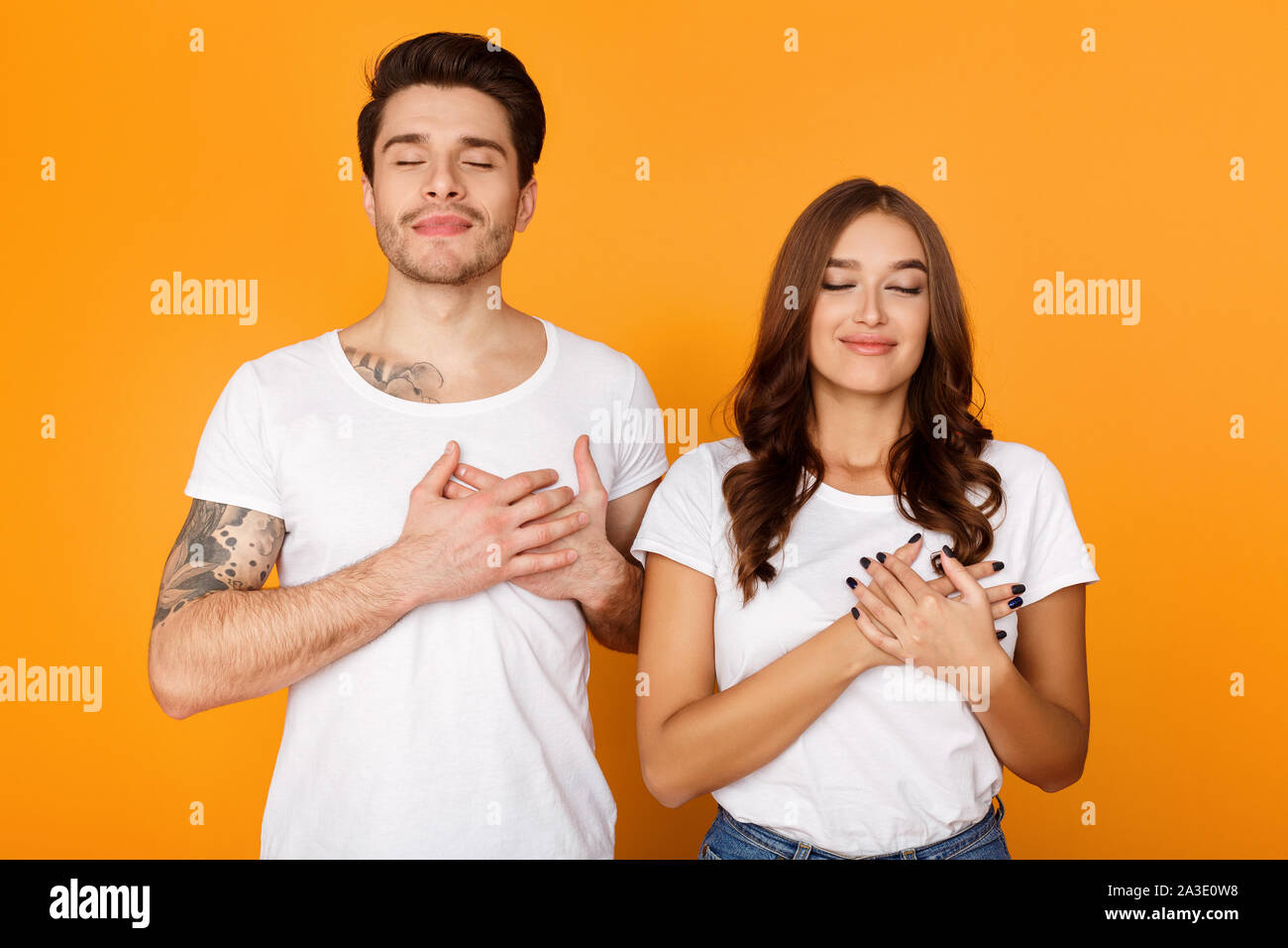 Kind woman and man keep both palms on chest Stock Photo - Alamy