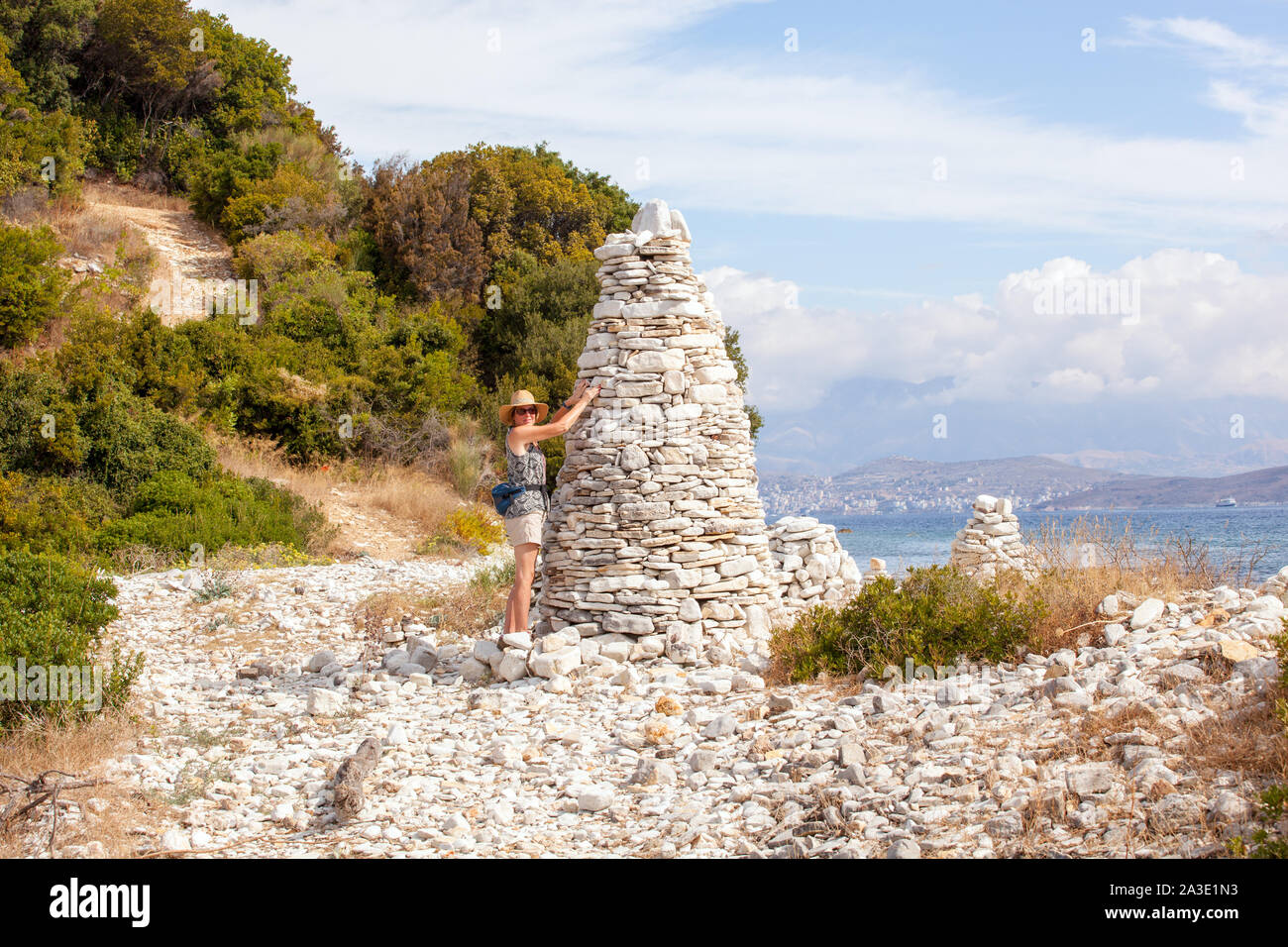 Woman placing laying a stone pebble on a cairn on the beach near the ...