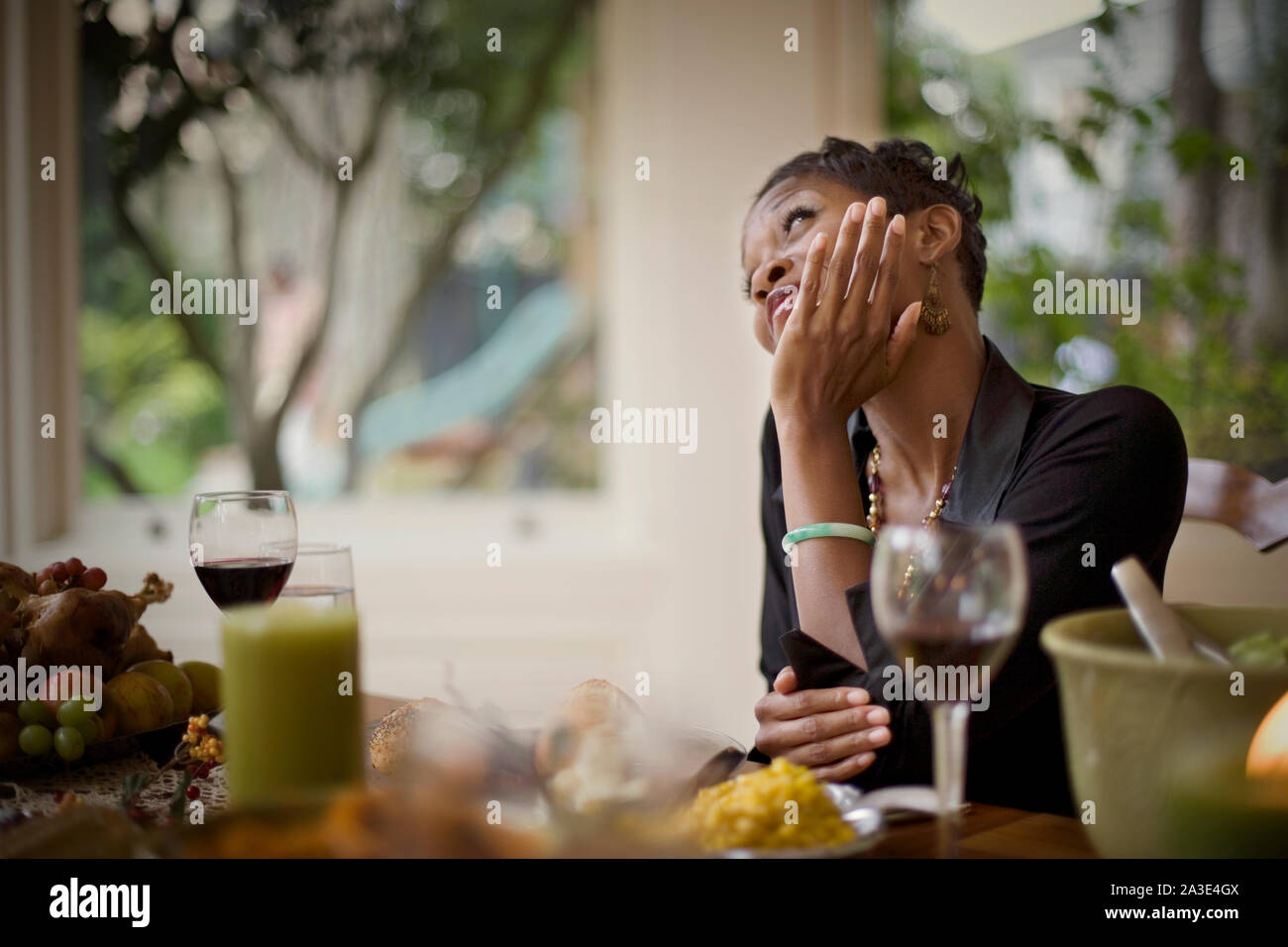 Mid-adult woman resting her chin in her hand at a dining table Stock ...