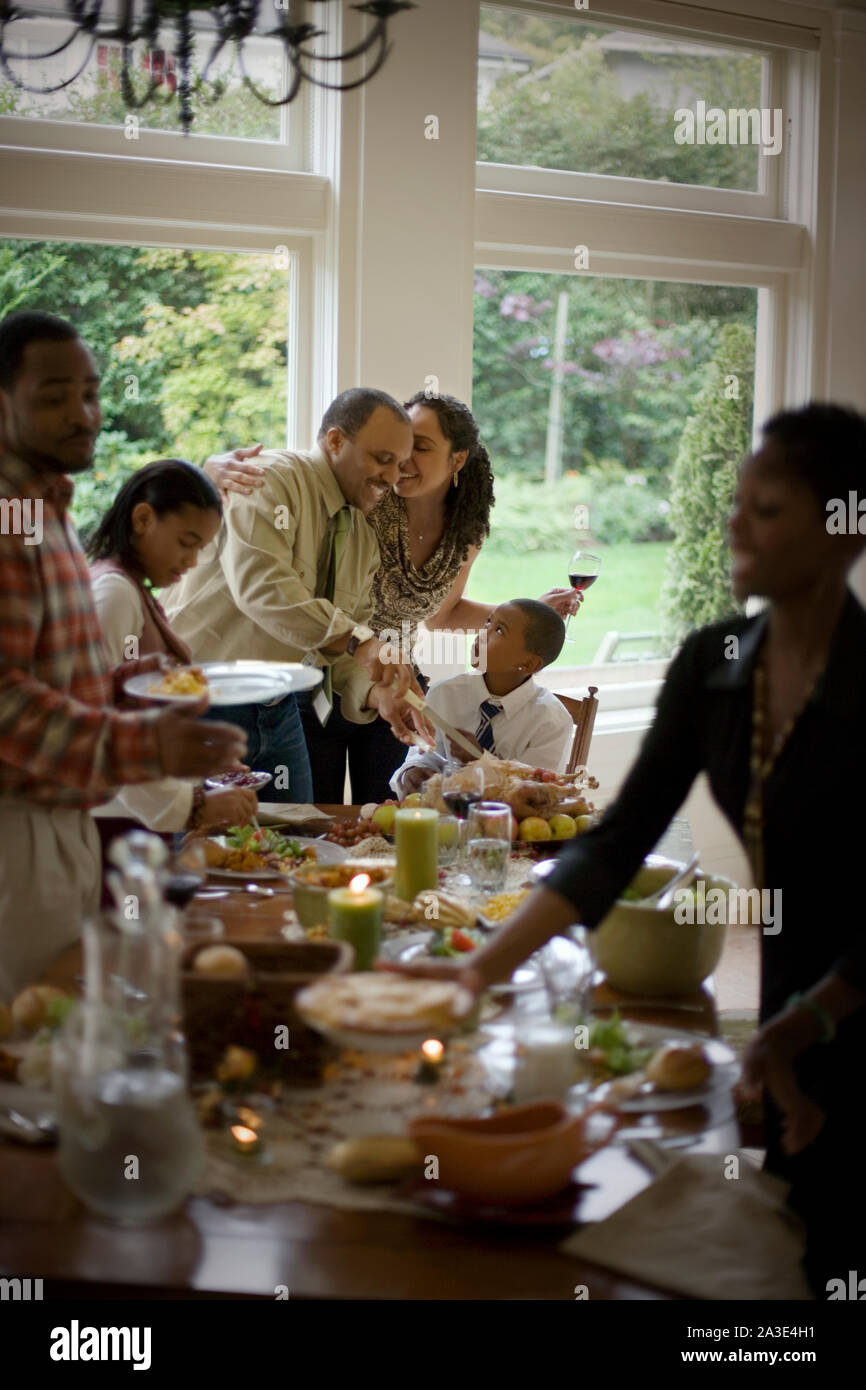 Smiling family gathered around a dining table Stock Photo - Alamy