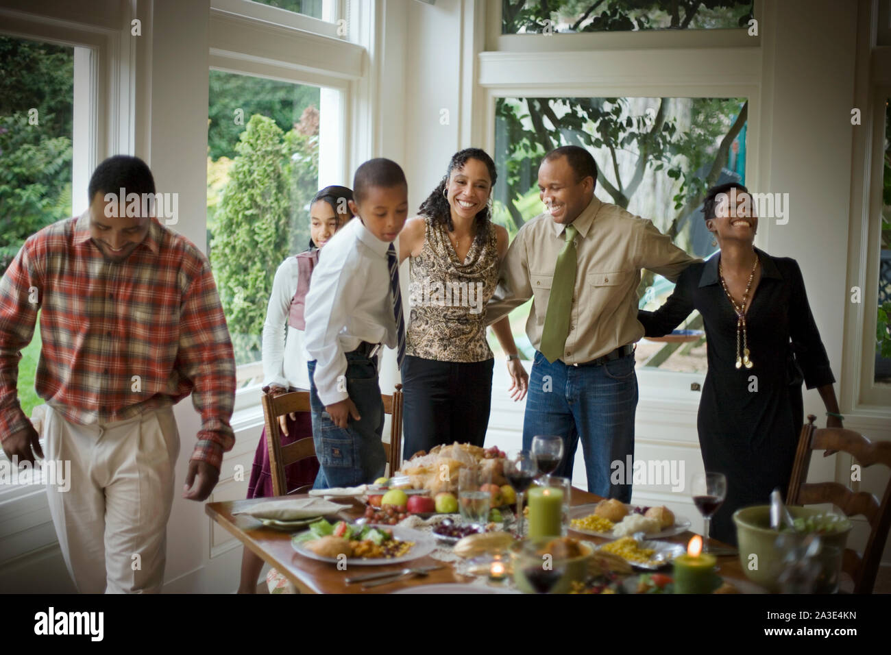 Smiling family gathered around a dining table Stock Photo - Alamy