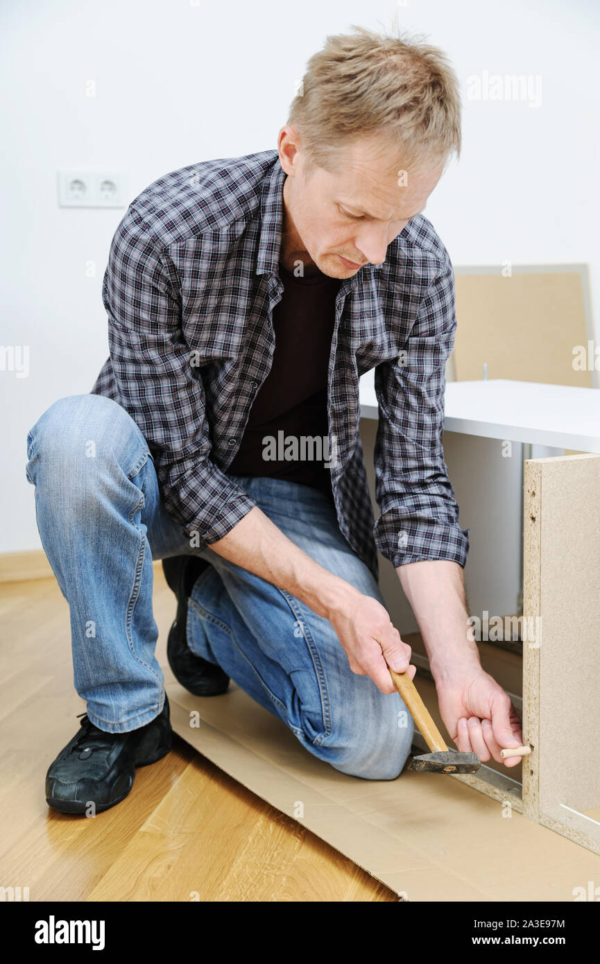 The man is hammering a wooden pin into a furniture board Stock Photo ...