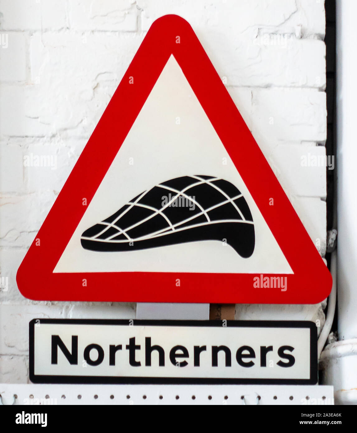 Cloth cap on triangle warning sign saying Northerners Stock Photo - Alamy