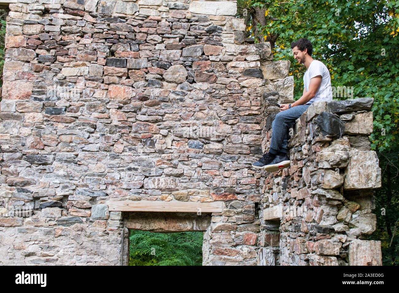 young man with cell phone outdoors on wall of abandoned building Stock ...