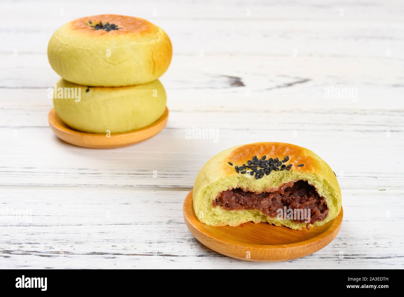 side view cut out red bean paste cake with two complete ones on a wood ...