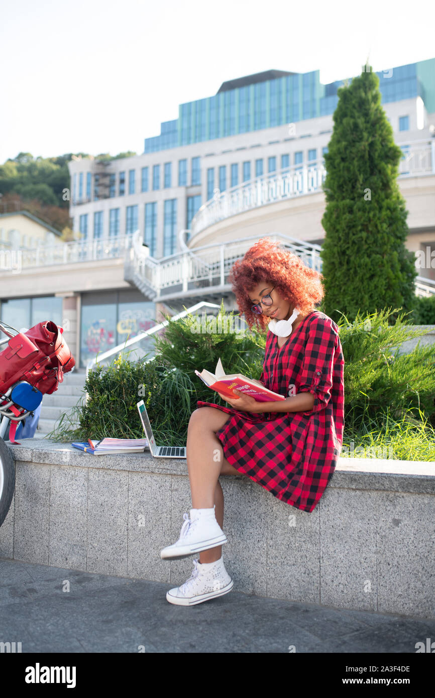 Curly student feeling busy while preparing for test outside Stock Photo ...