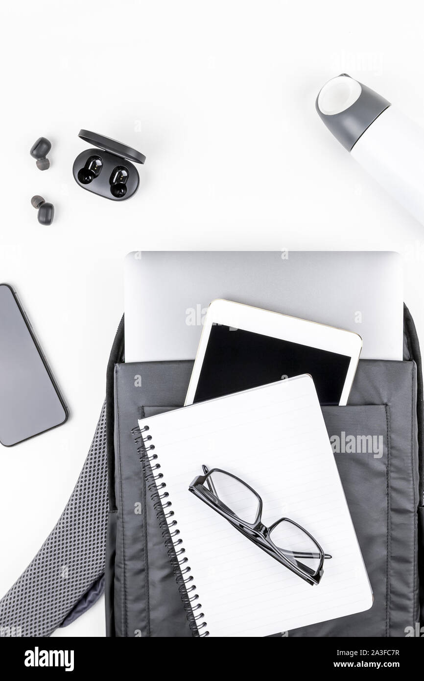 Creative top view flat lay of open backpack with laptop and tablet ...
