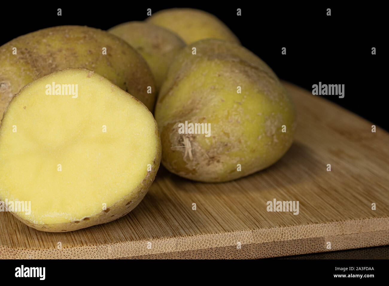 Group of five whole one half of raw brown potato on bamboo cutting ...