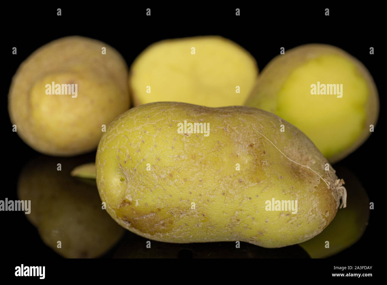Group of three whole one half of raw brown potato isolated on black ...
