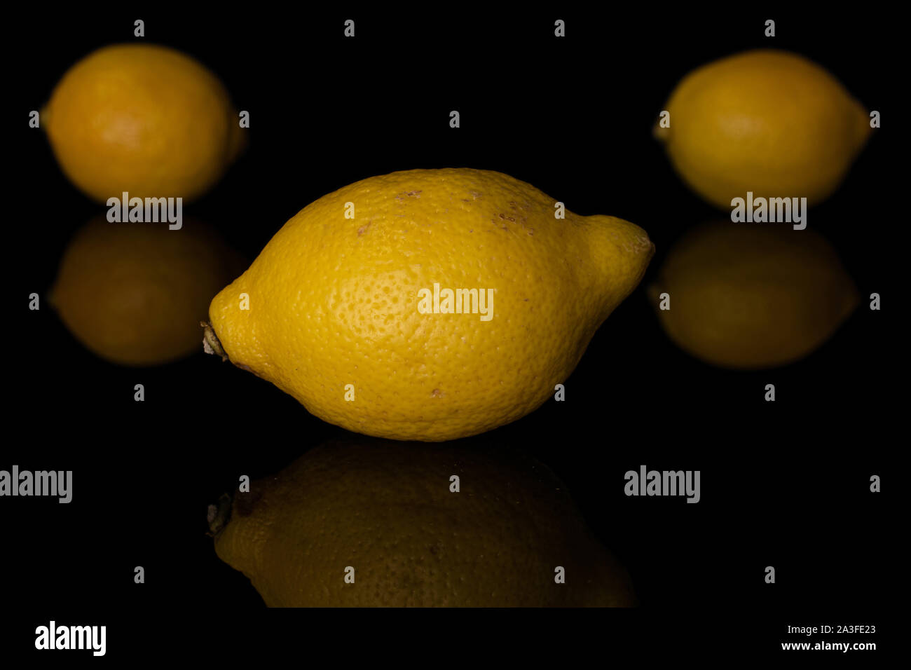 Group of three whole fresh yellow lemon front focus isolated on black ...