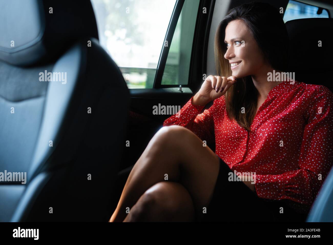 Beautiful smiling dreaming businesswoman sitting on back seat of the ...