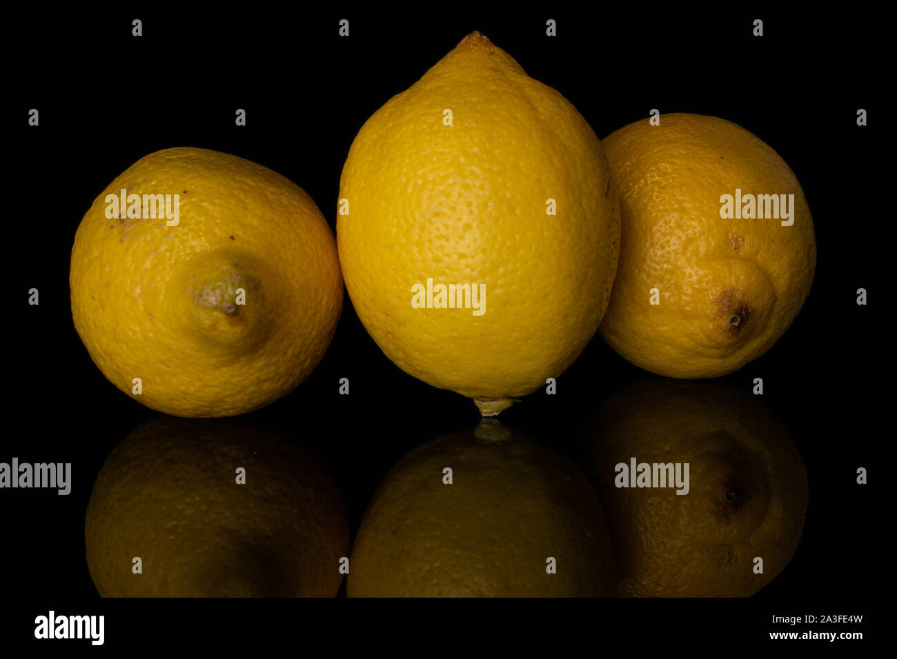 Group of three whole fresh yellow lemon isolated on black glass Stock ...