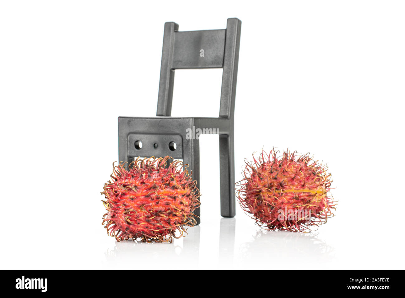Group of two whole fresh red rambutan with black chair isolated on ...