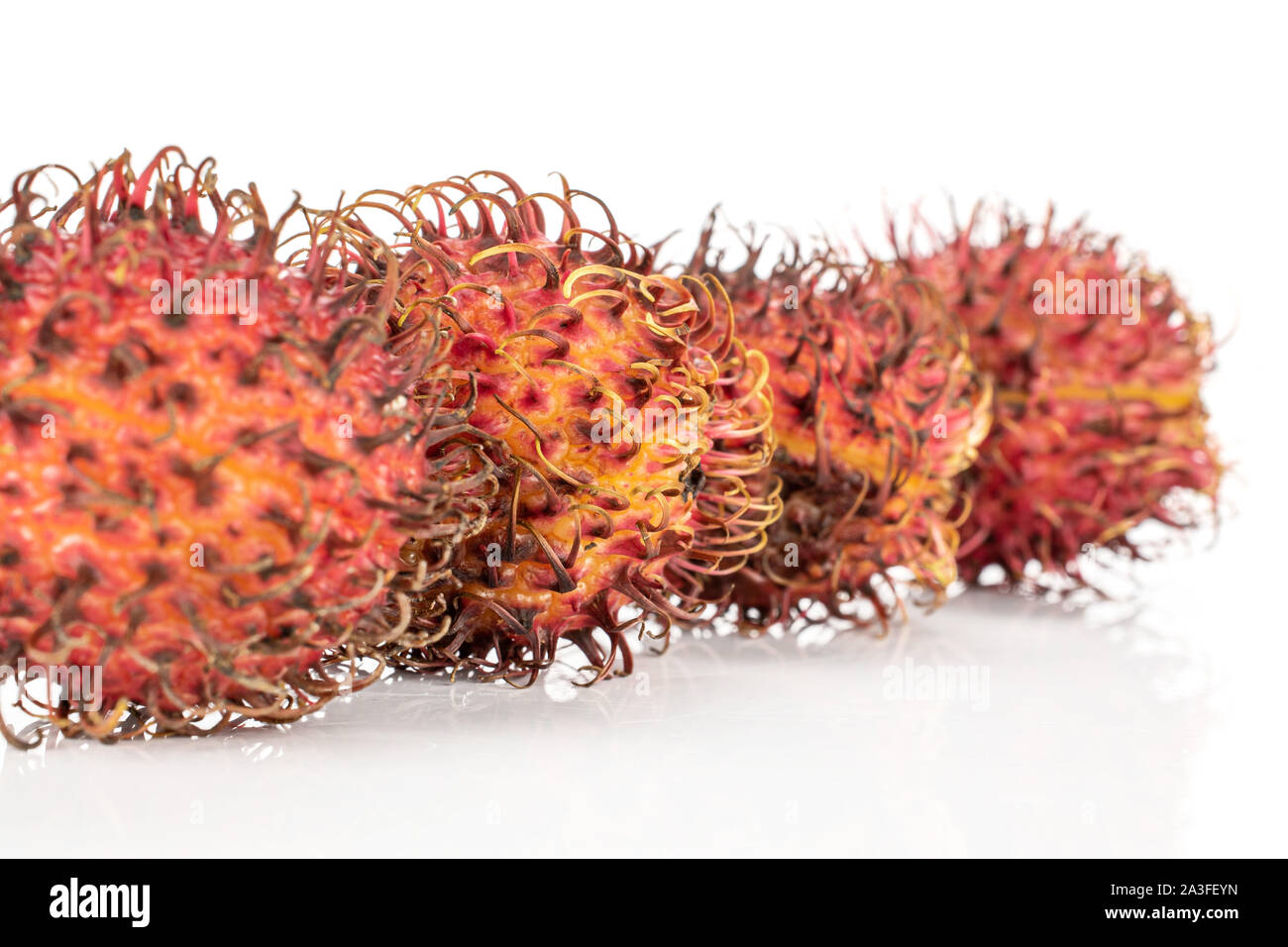 Group of four whole unpeeled fresh red rambutan in row isolated on ...