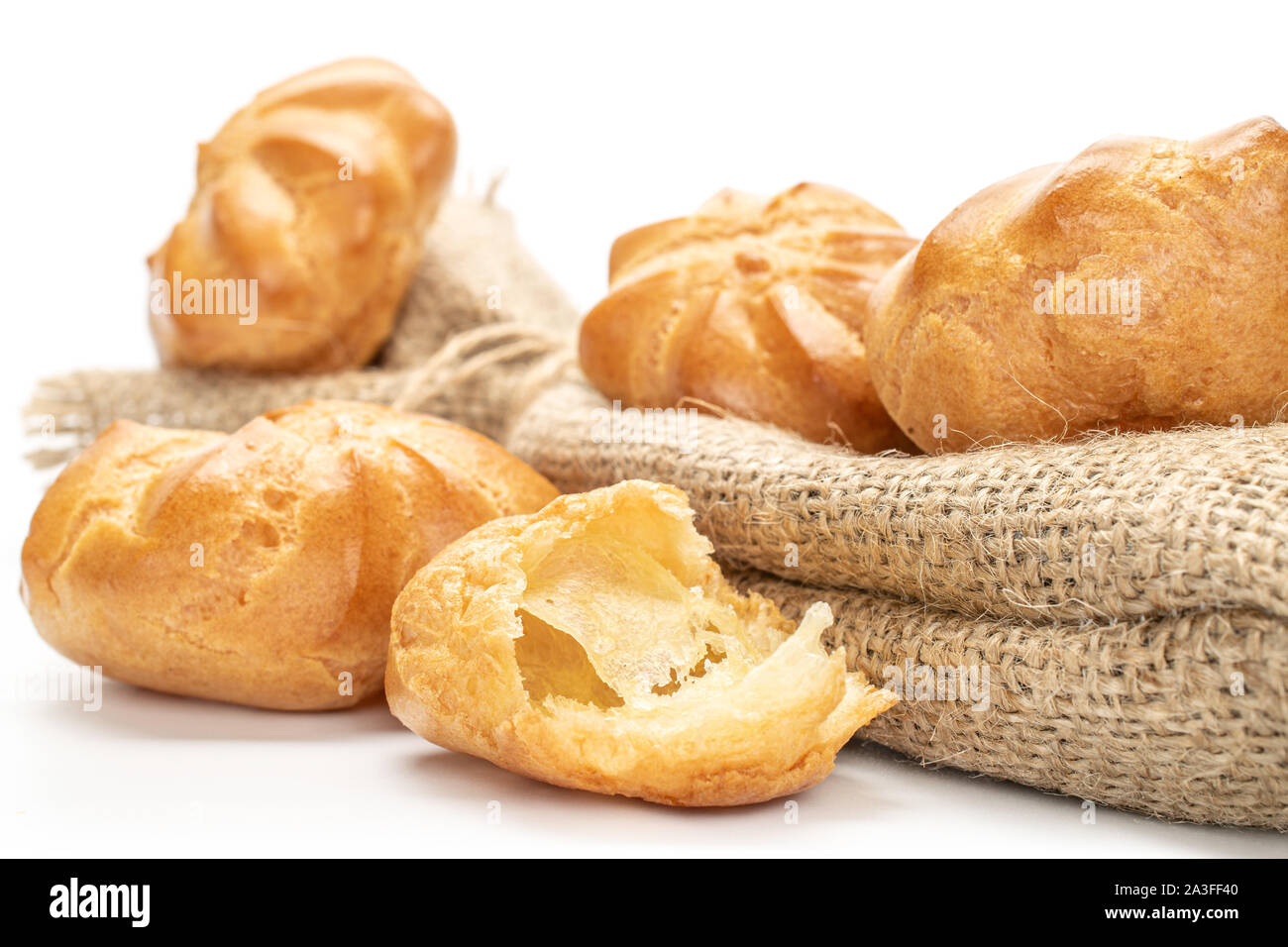Group of four whole one half of baked golden profiterole with jute bag ...