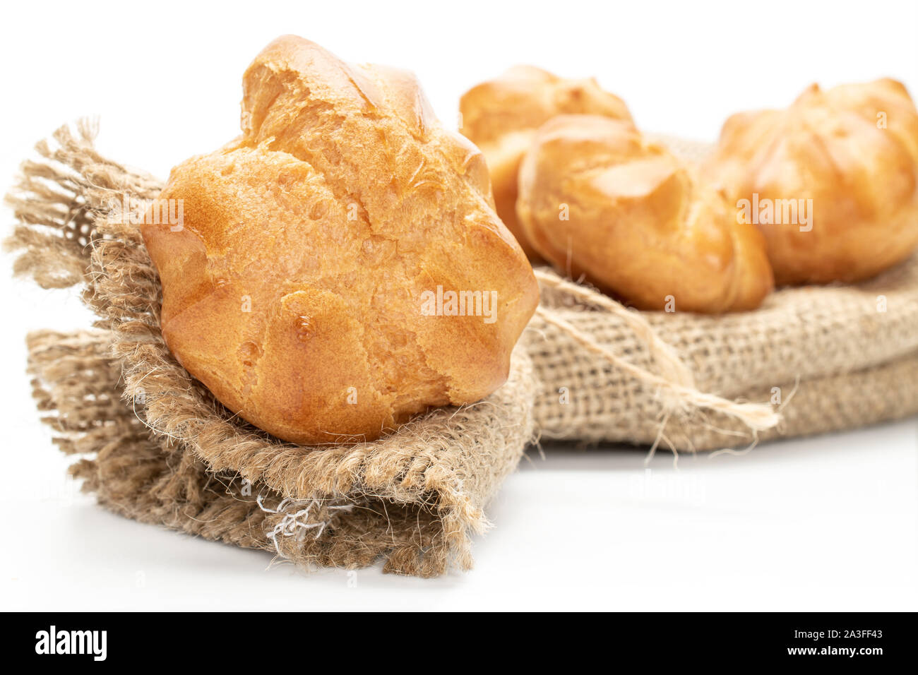 Group of four whole baked golden profiterole with jute bag isolated on ...