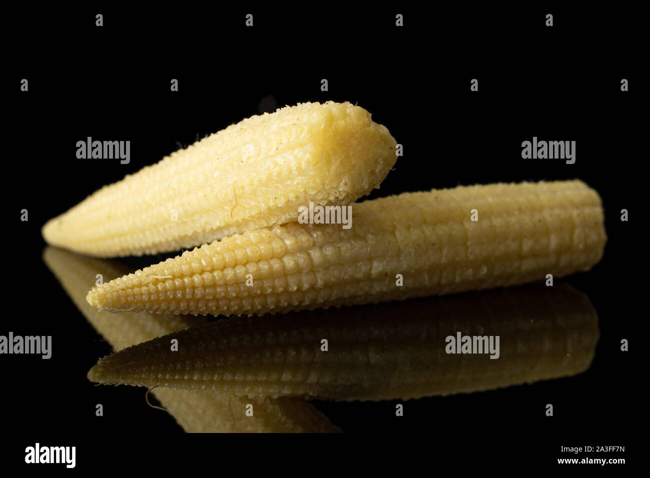 Group of two whole baby yellow corn isolated on black glass Stock Photo ...