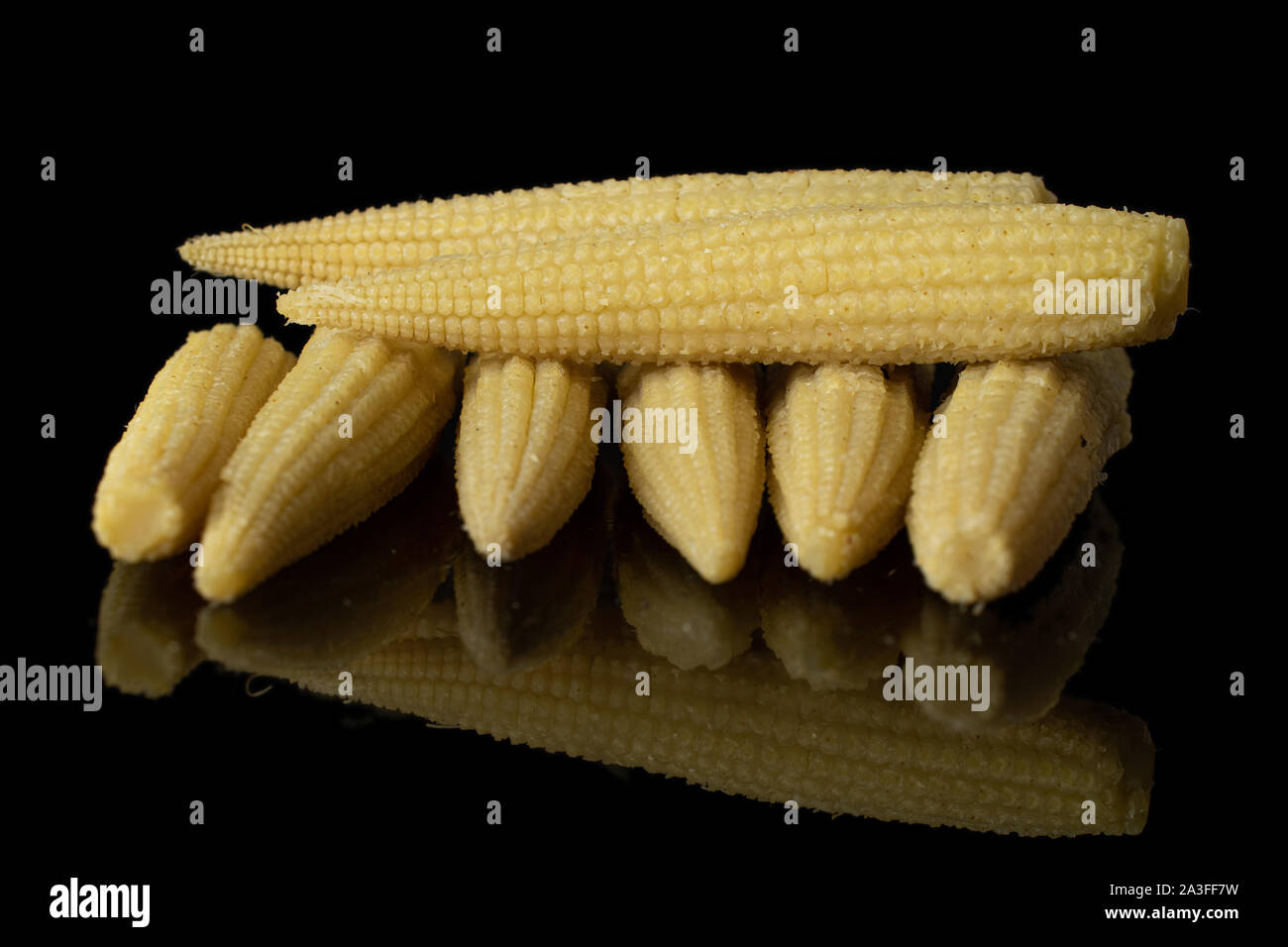 Group of eight whole baby yellow corn isolated on black glass Stock ...