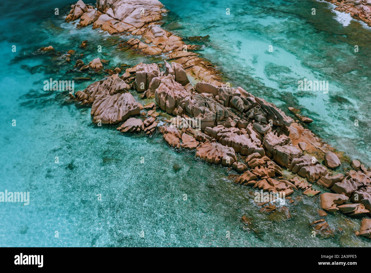 Aerial top view of granite rock formation surrounded by blue ocean ...