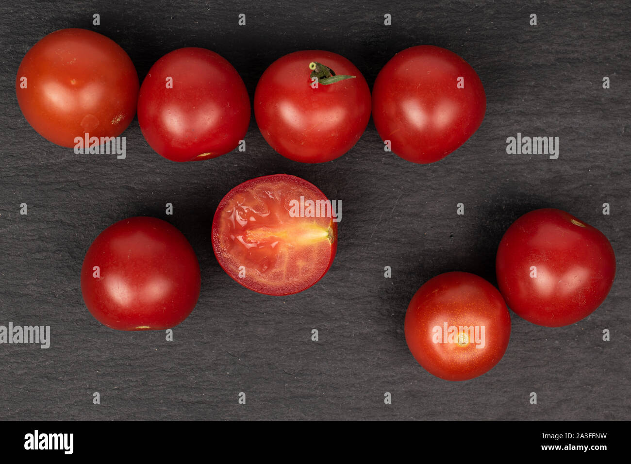Group of seven whole one half of fresh red tomato flatlay on grey stone ...