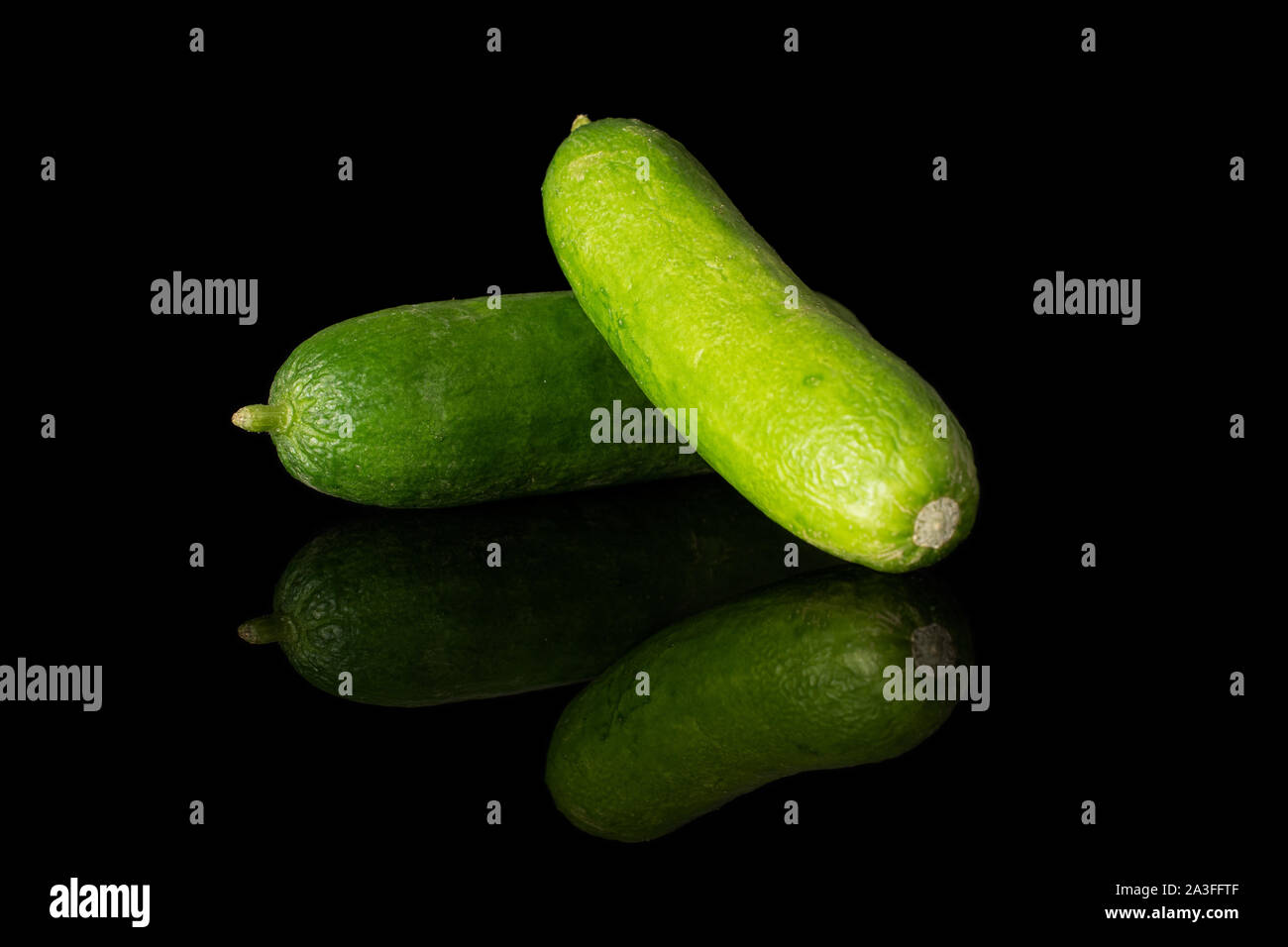 Group of two whole mini green cucumber isolated on black glass Stock ...