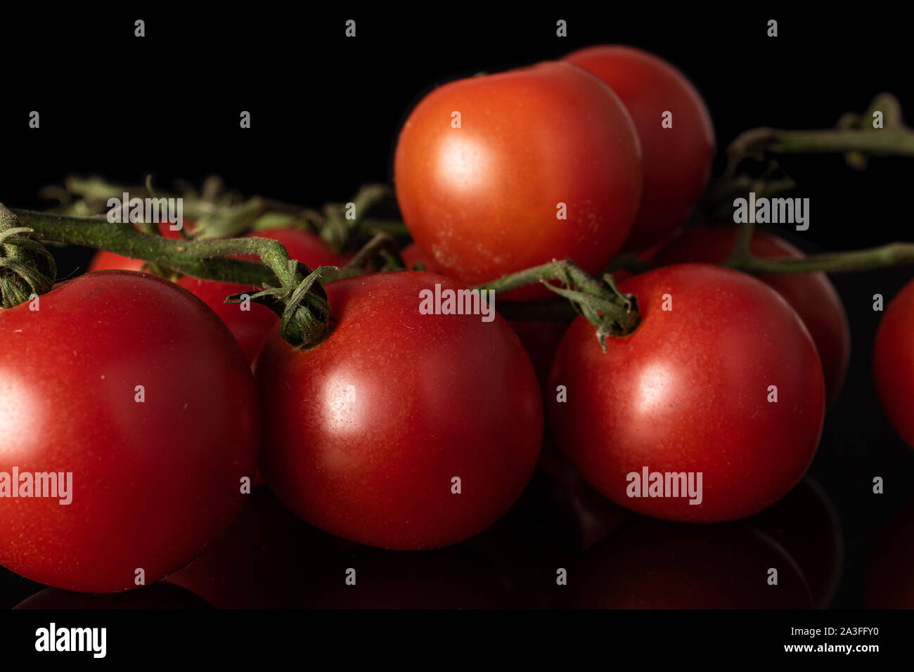 Lot of whole fresh red tomato cluster isolated on black glass Stock ...