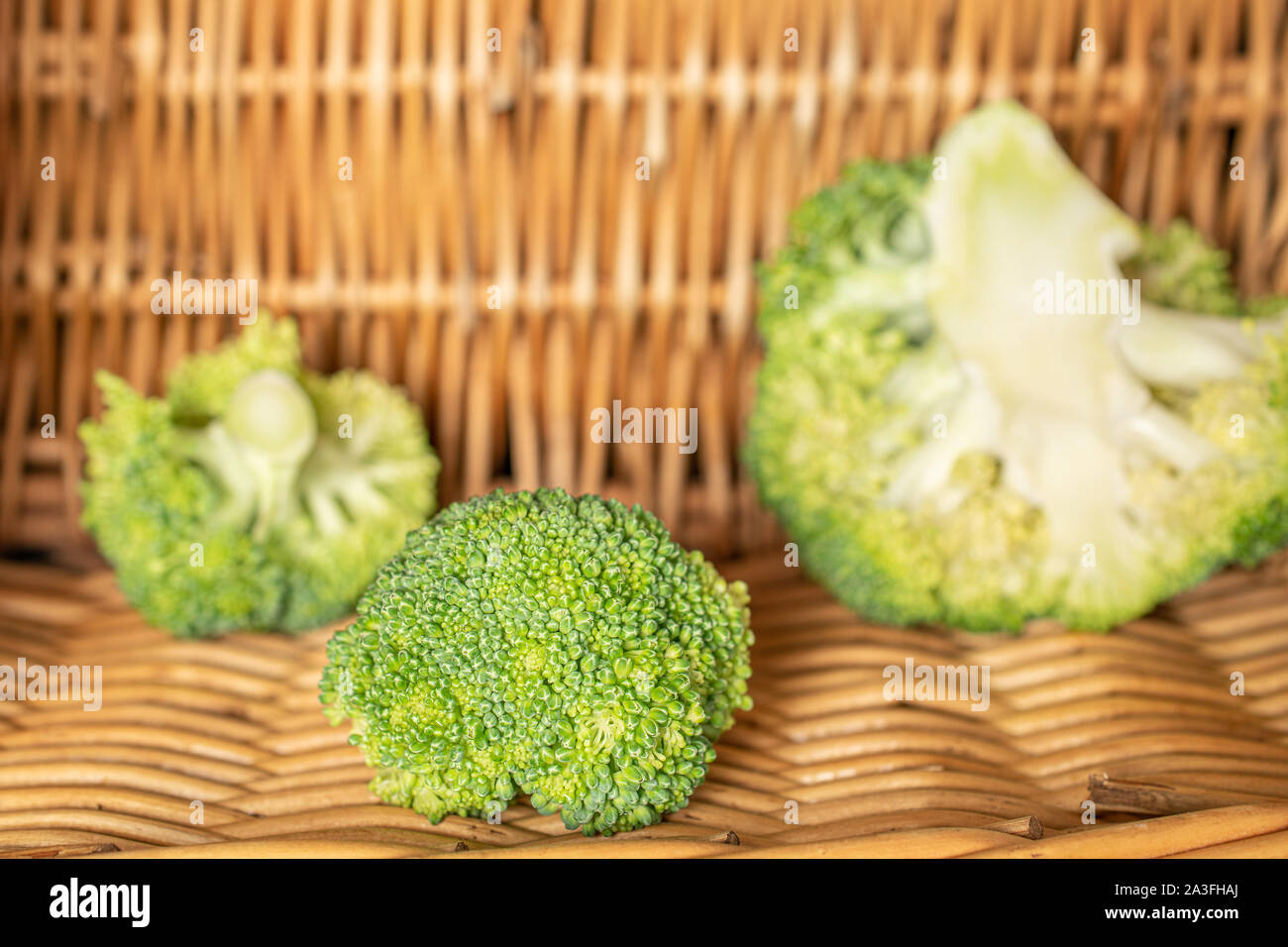 Group of two whole one half of fresh green broccoli with braided rattan ...