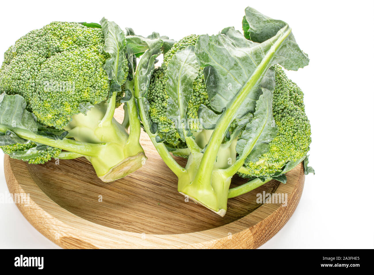Group of two whole fresh green broccoli cluster on bamboo plate ...