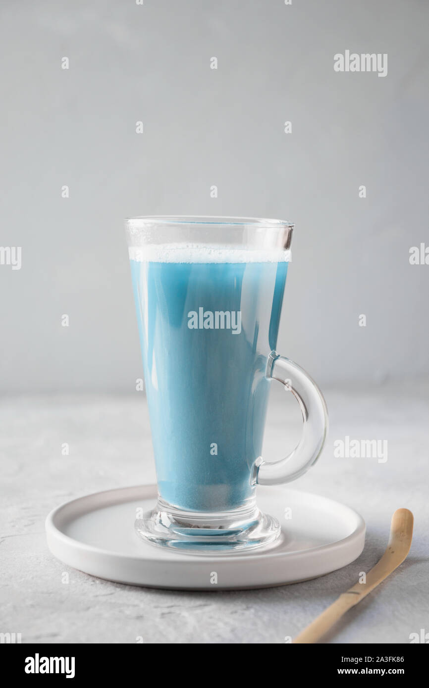 Blue matcha tea in latte glass on grey table. Space for text. Close up ...