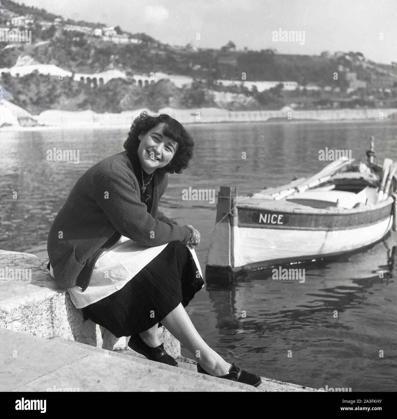 1950s, historical, a female waitress sitting by the water's edge at ...