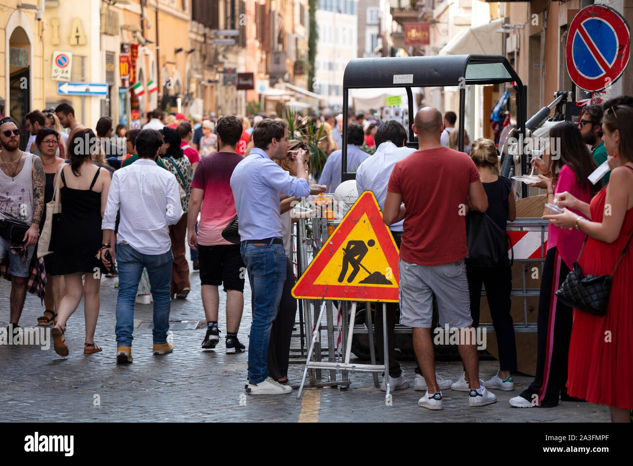 People standing on a busy street in central Rome eating street food ...