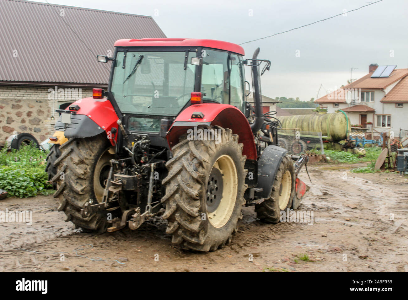 Red tractor and agricultural equipment in the yard of a dairy farm ...