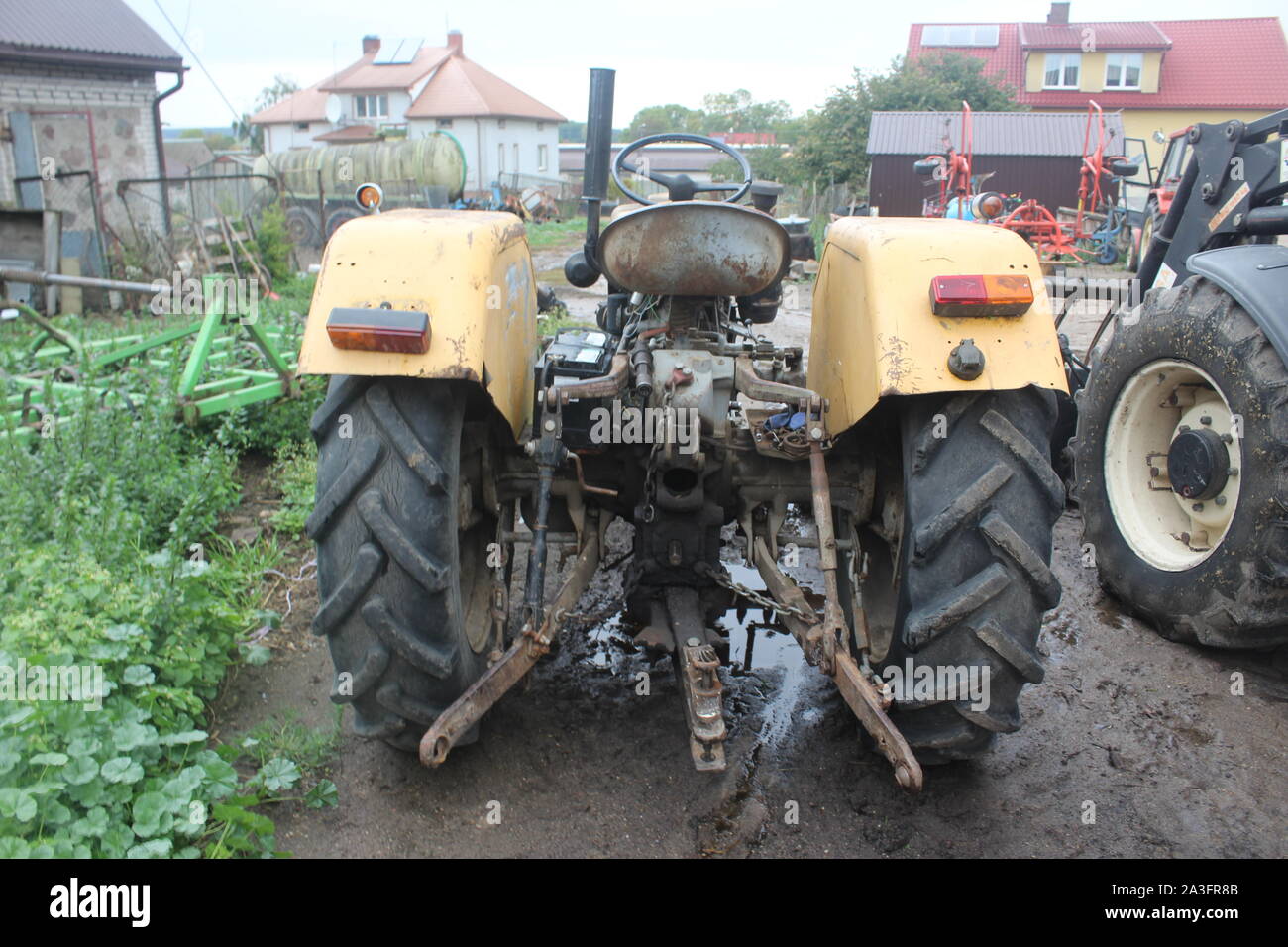 Yellow tractor without a cab in the courtyard of a dairy farm. View ...