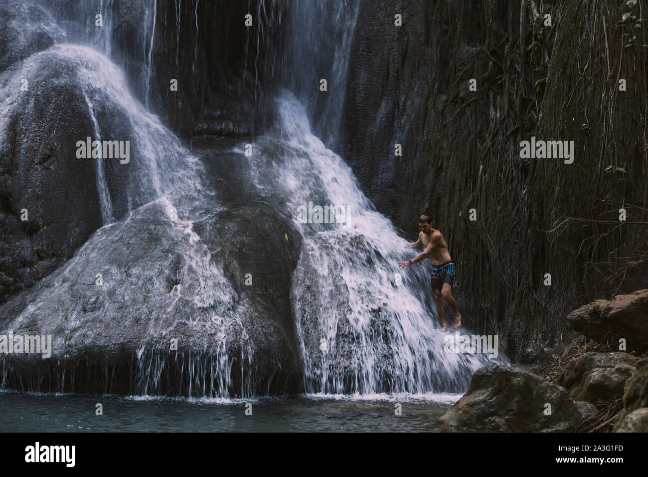 Man standing under waterfall Stock Photo - Alamy