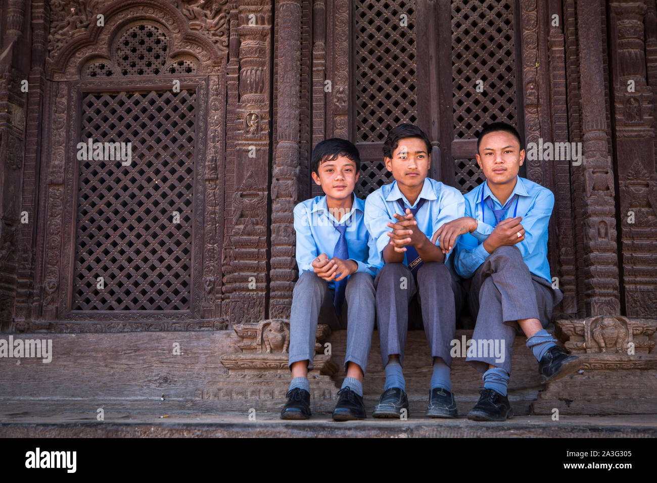 Students in school uniforms sit outside a temple in Kathmandu, Nepal ...