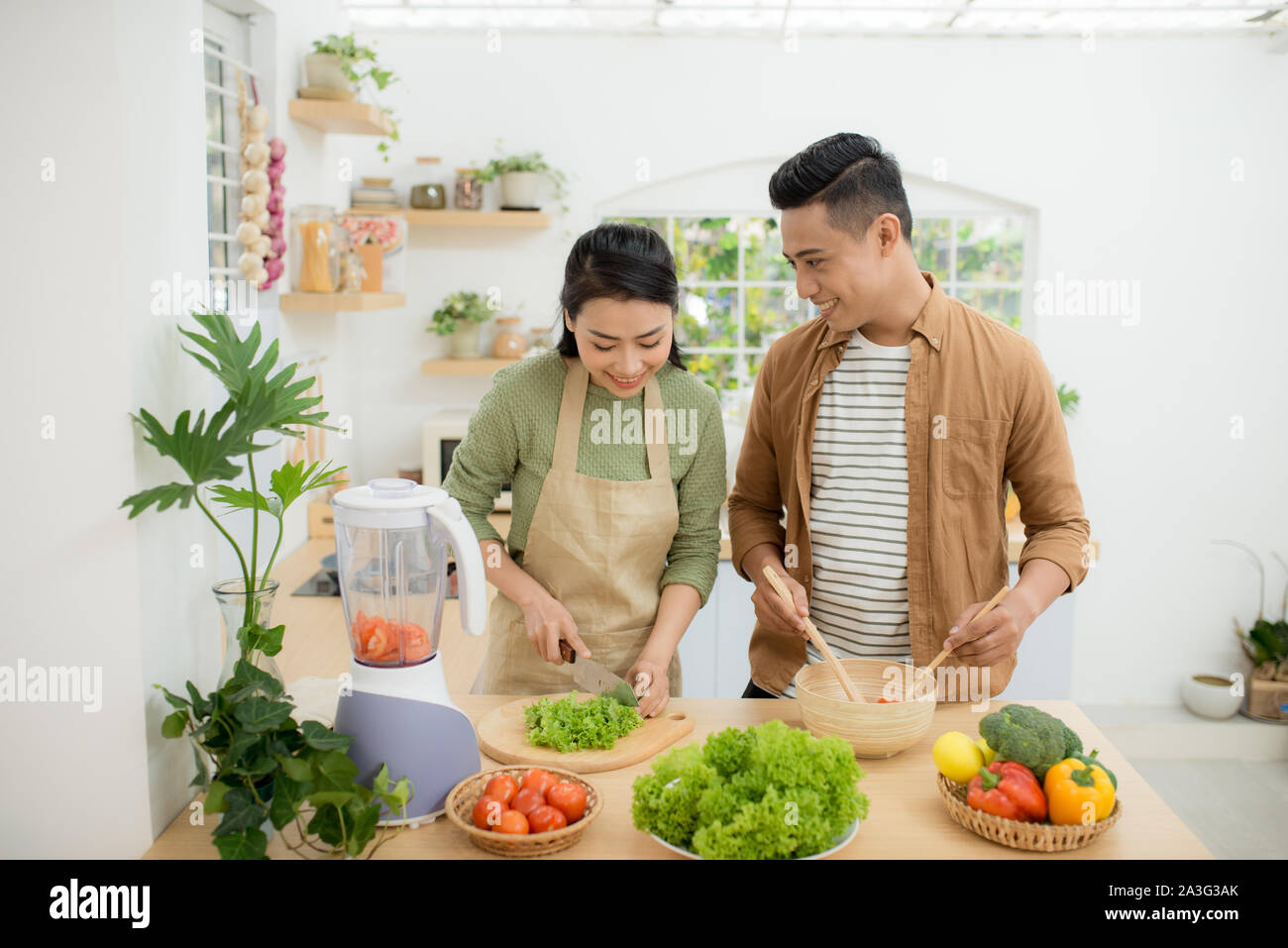 Smiling young Asian couple cooking food in the kitchen Stock Photo - Alamy