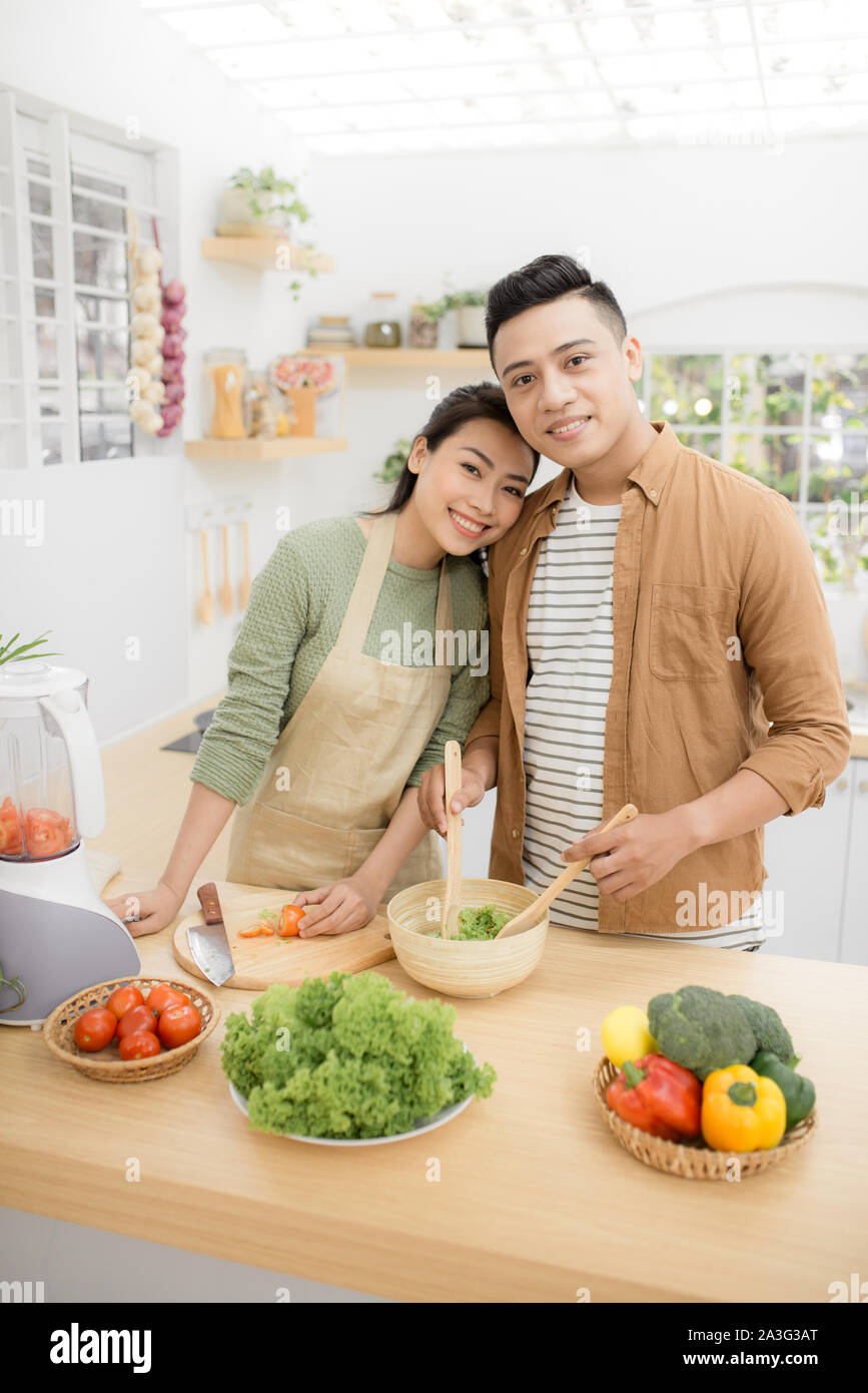 Smiling young Asian couple cooking food in the kitchen Stock Photo - Alamy