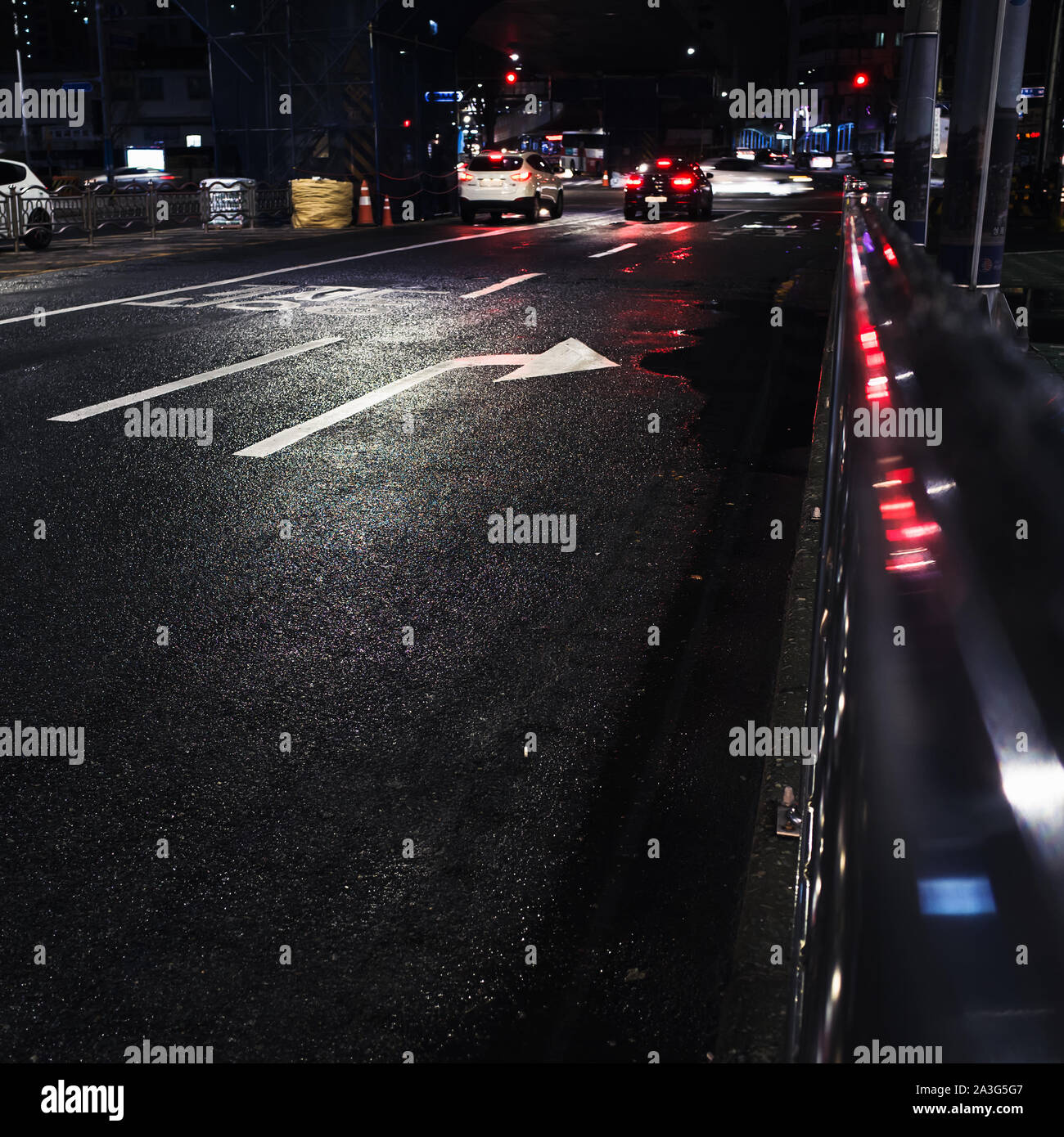 Square urban night photo with road marking arrows and red lights ...