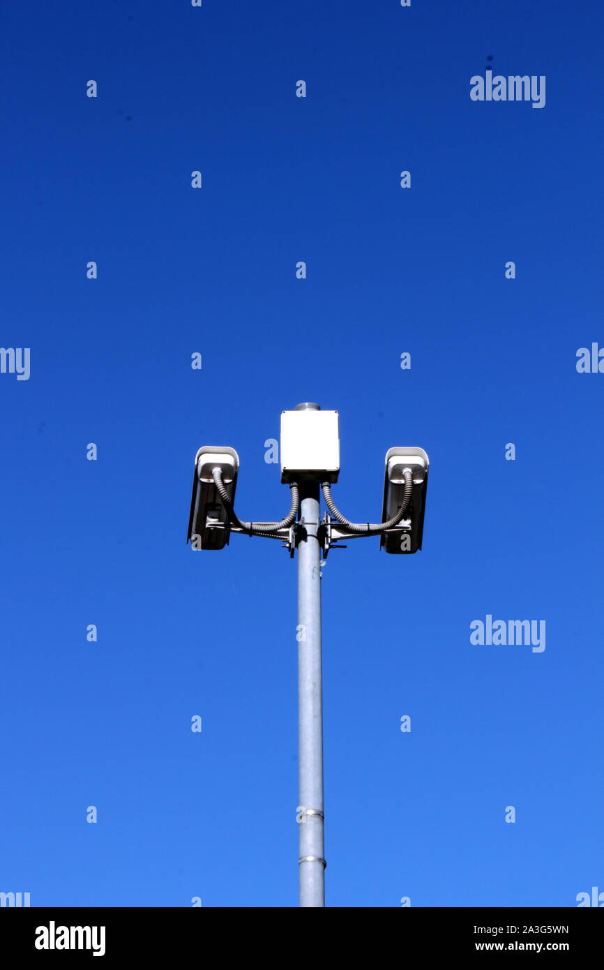 Upright view of security cameras on tall pole against deep blue sky ...