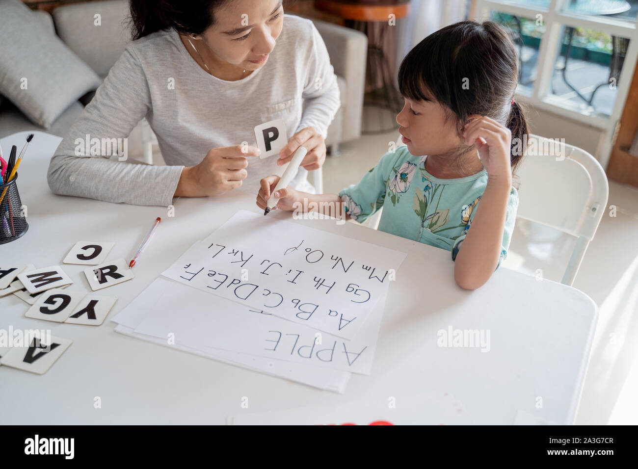 mother and daughter learning to read and write letter at home together ...